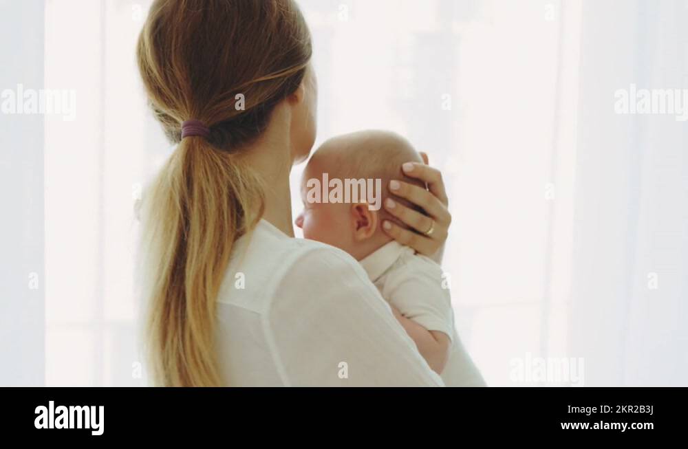 Back view of the caucasian mother holding and swings her newborn baby ...