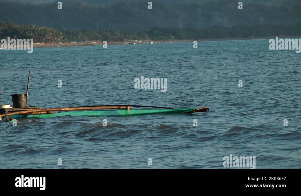 Filipino woman catching Milkfish fry in shallow water in Philippines ...