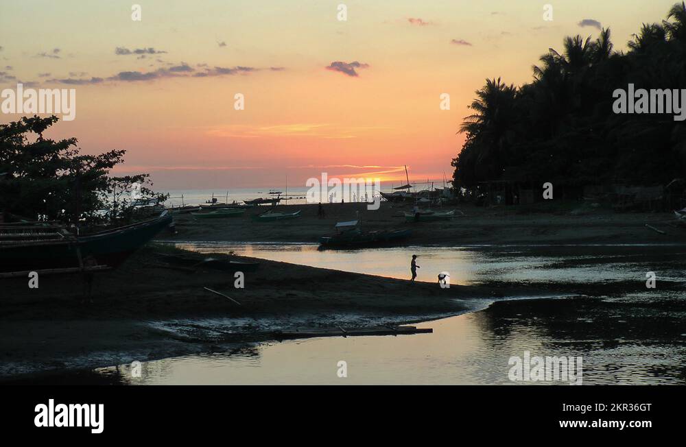 Children playing on Datu Sumakwel Beach during a vivid sunset in ...
