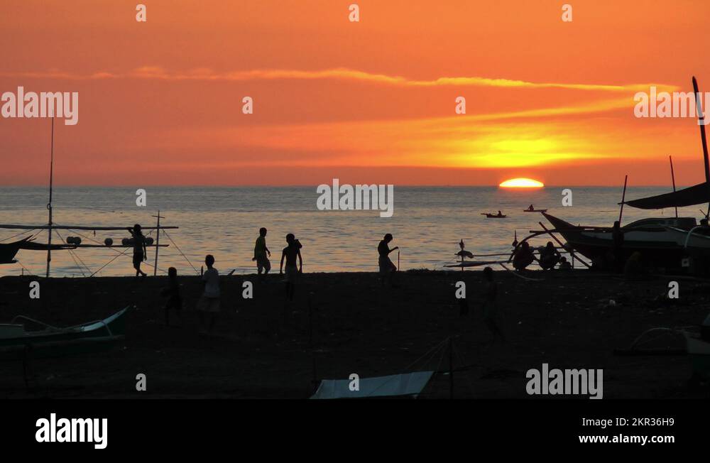 Children playing on Datu Sumakwel Beach during a vivid sunset in ...