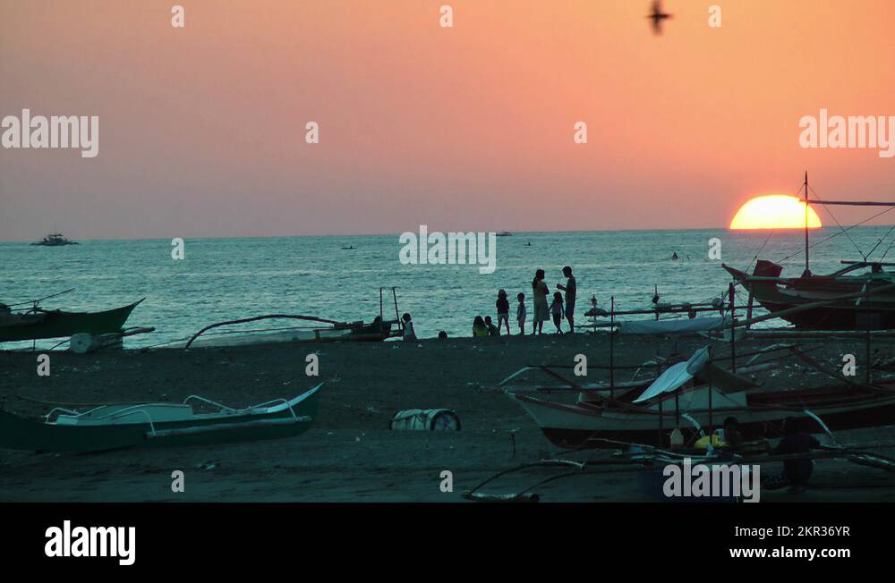 People walking on Datu Sumakwel Beach during sunset in the Philippines ...