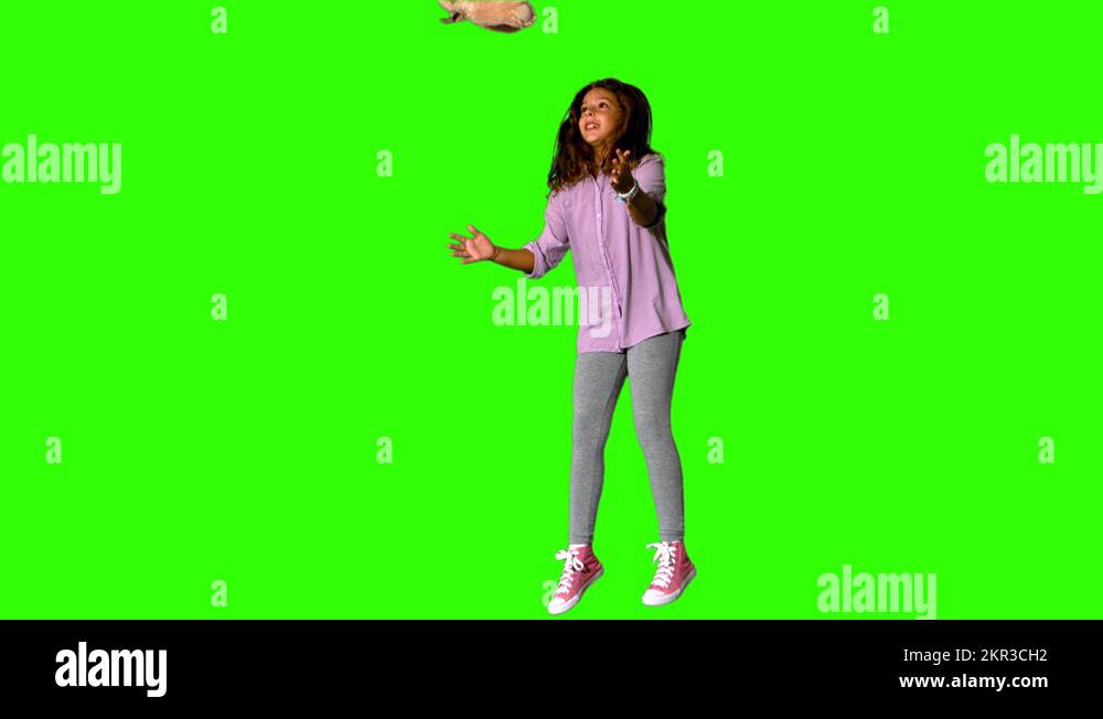 Happy little girl jumping up and catching teddy on the green screen ...