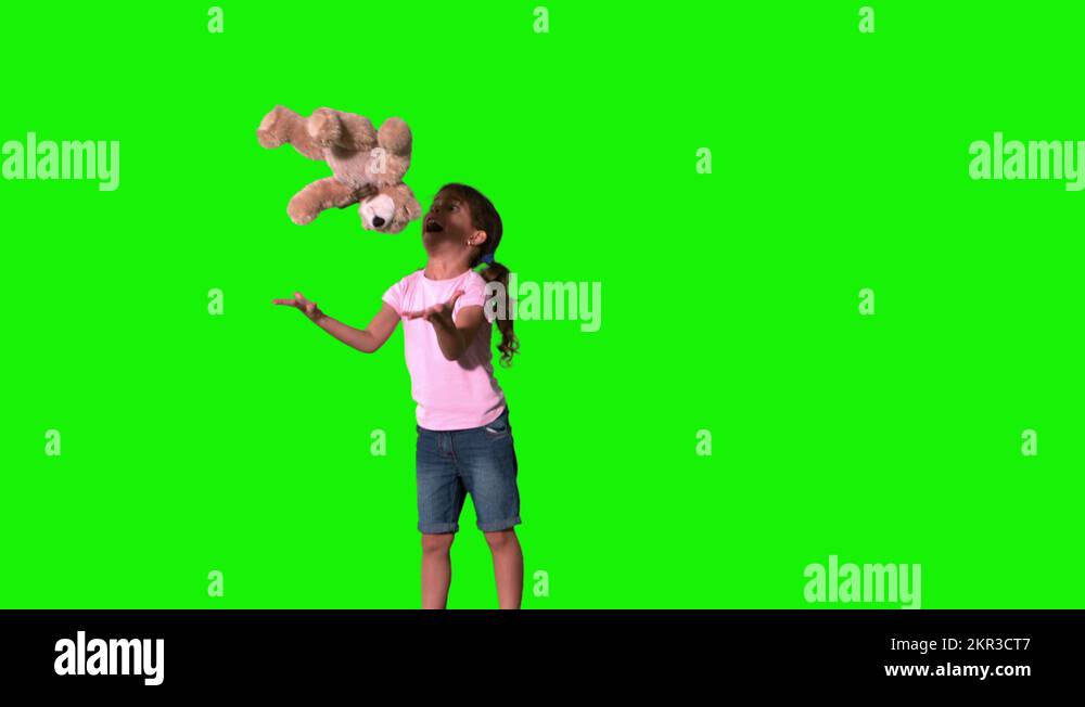 Cute little girl jumping and catching teddy on green screen Stock Video ...