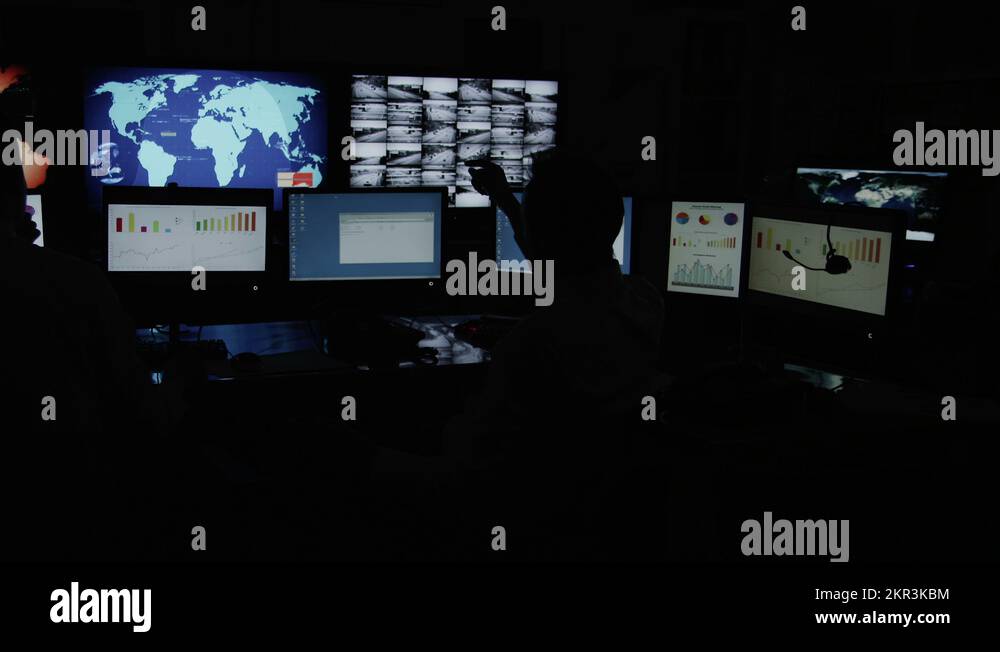 Security personnel watching the screens in a dark system control room ...