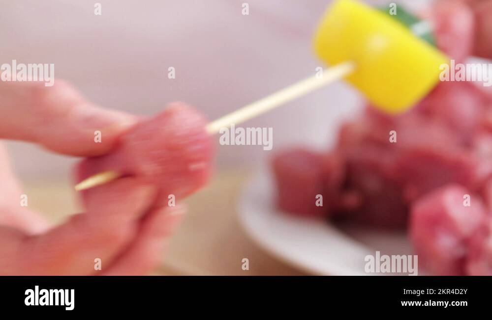 Threading cubes of meat and vegetables onto a wooden skewer Stock Video ...