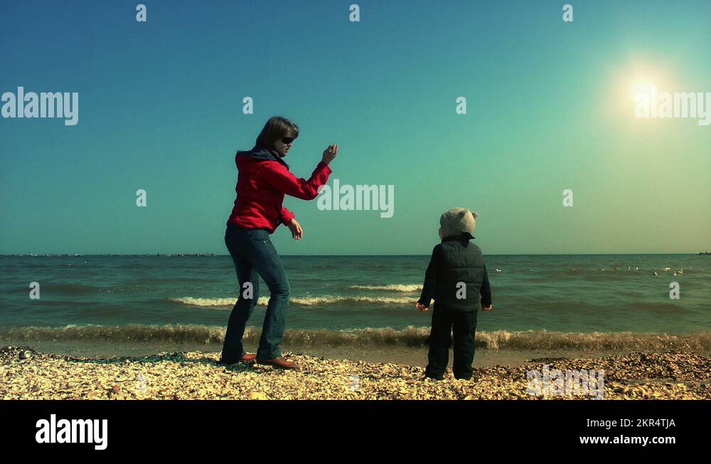 Mother teaching her son to throw sea shells Stock Video Footage - Alamy