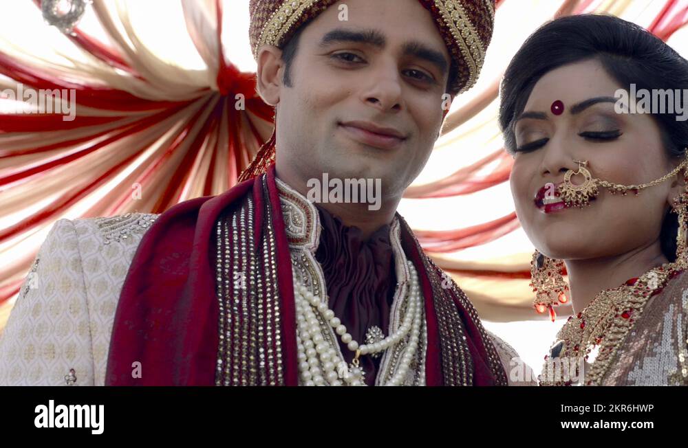 Shot of Indian bride and groom in traditional wedding dress under a ...