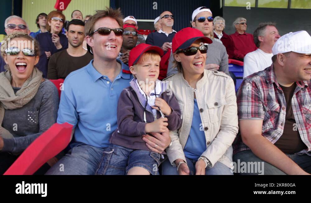 Boy with family in crowd of sports spectators. Could be a stadium crowd ...