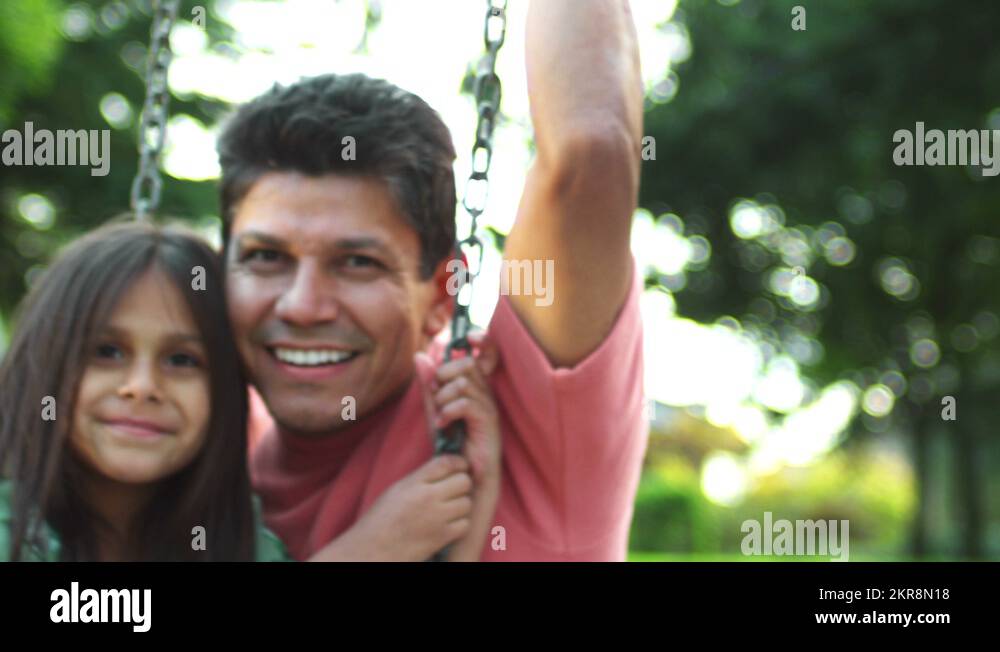 Cute little girl kisses her fathers cheek as they swing together Stock Video Footage - Alamy