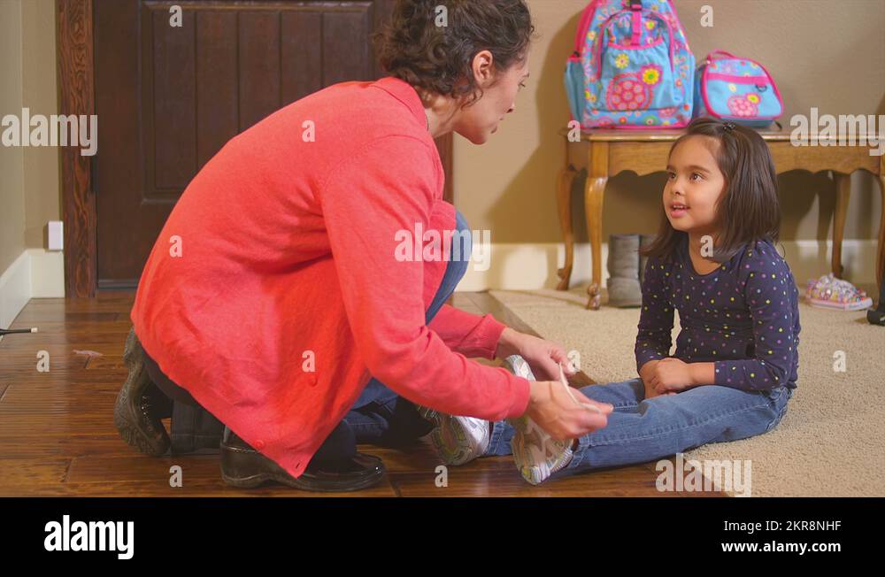 A cute little girl gets help from her mother while getting ready for ...
