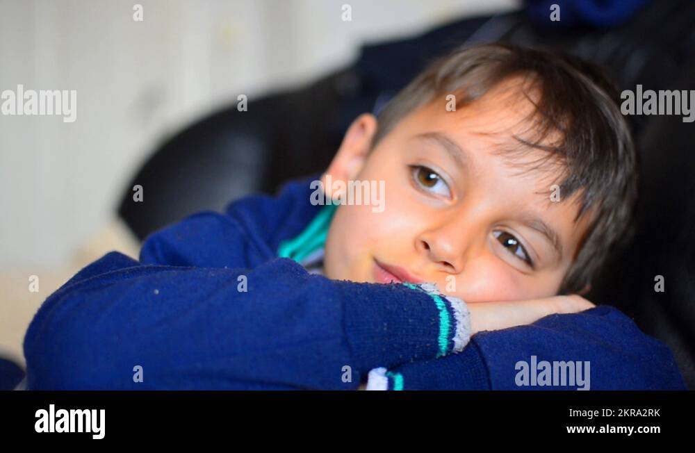 sleepy handsome boy lying on sofa and watching tv, afterwards look at ...