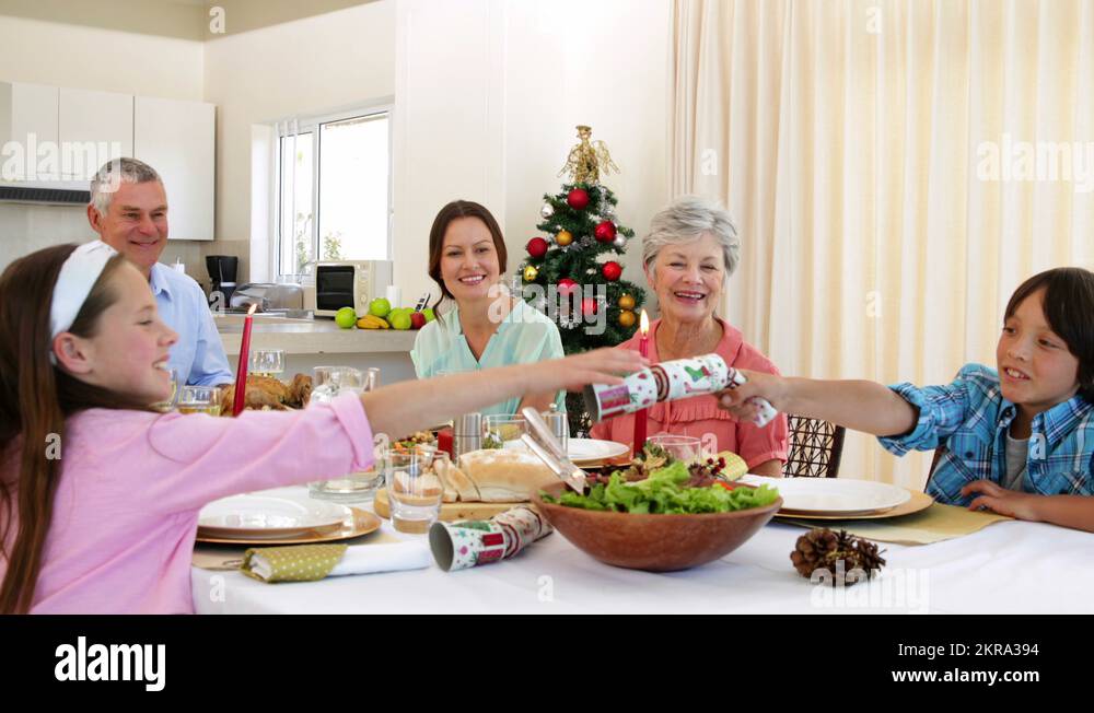 Brother and sister pulling a christmas cracker at the dinner table ...
