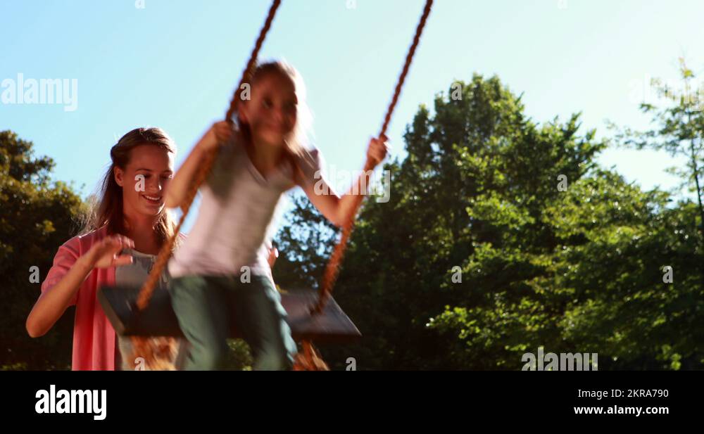 Little girl being pushed on a swing by her mother in the park Stock ...