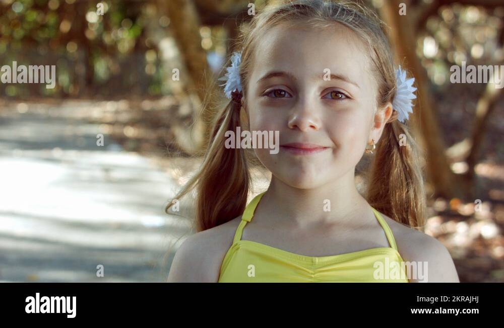 Cute Little Girl Smiles At Camera, Looks Over Her Shoulder, Back To ...