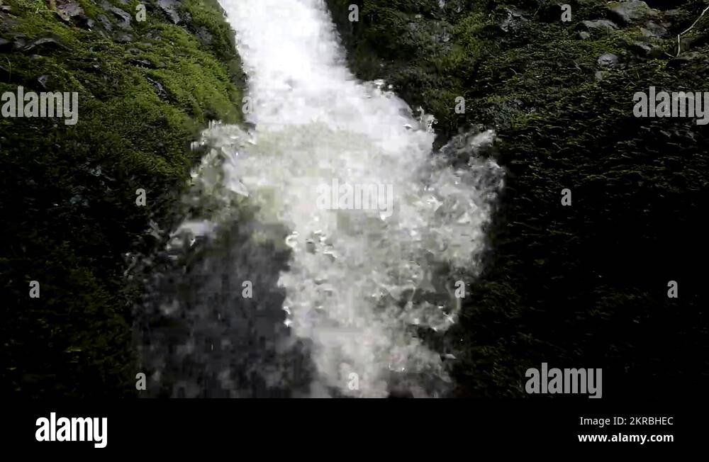 water is running trough big crack in basalt boulder and bubbles create ...
