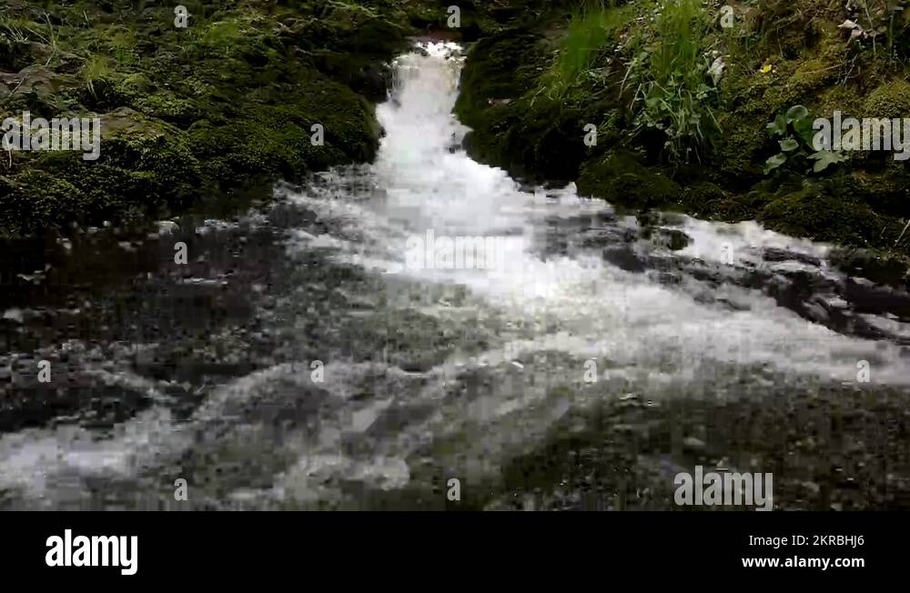 Cascade on small mountain stream, water is running trough big crack ...