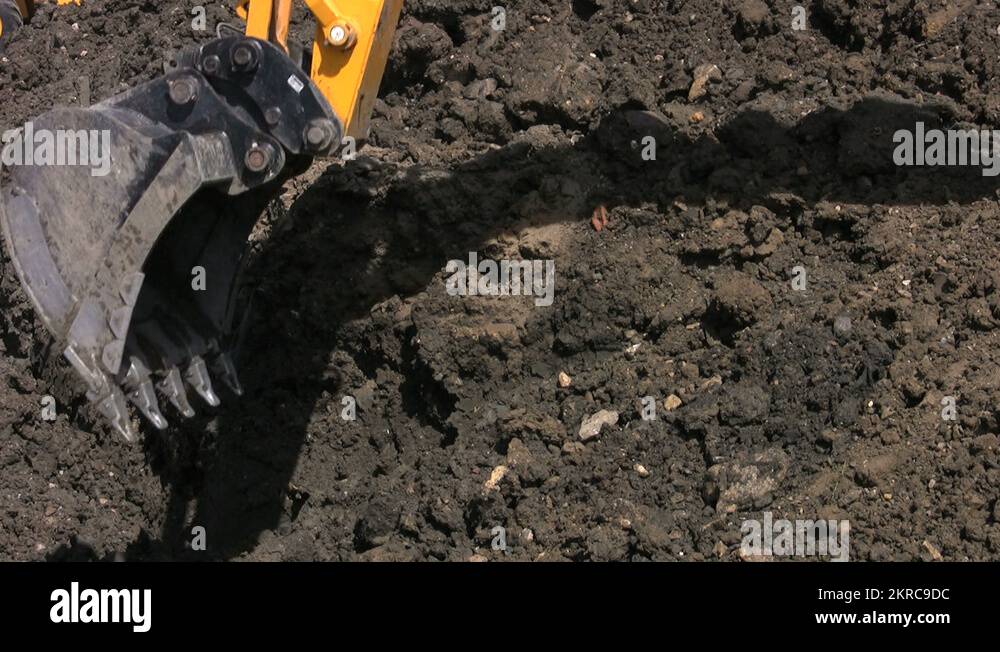 Excavator bucket digging a hole. Earthworks dig on a building site ...