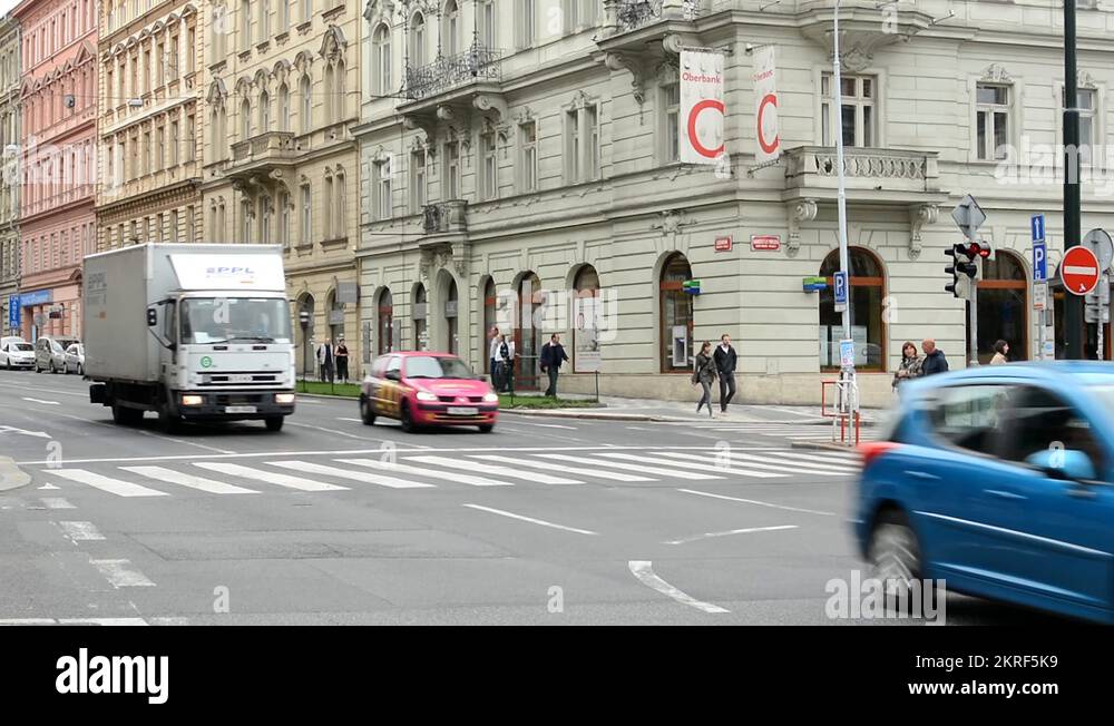 urban street with passing cars and pedestrian crossing: people walking ...