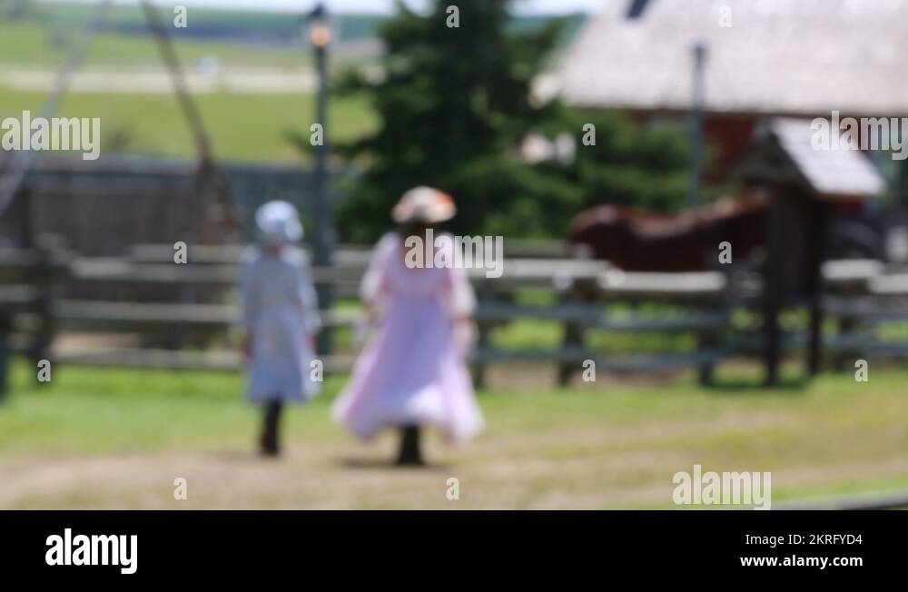 Rack Focus on Two Girls in Western Era Clothing Walking Near a Corral ...