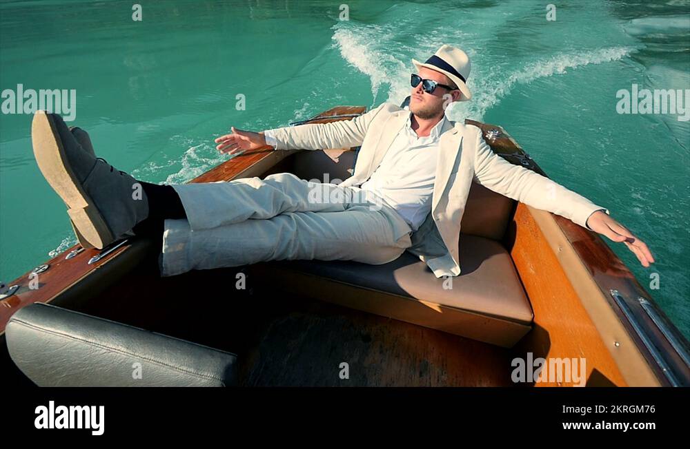 casual dressed man enjoying easy life on boat ride. raising hand pose ...