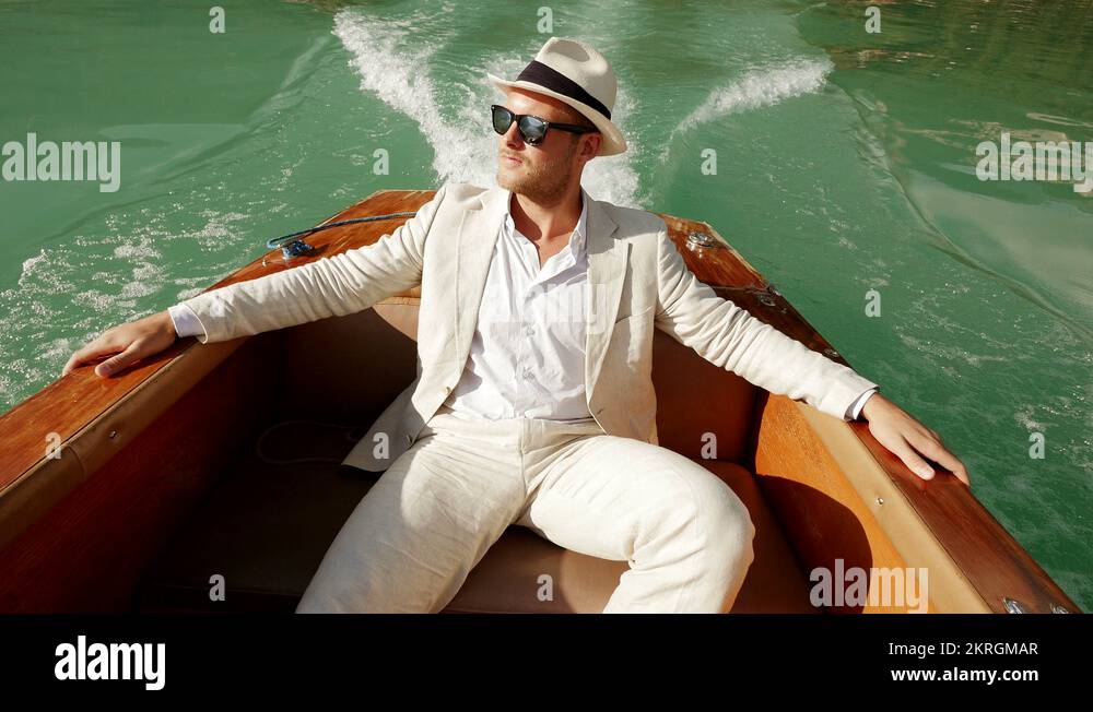 relaxed single man in casual suit enjoying life on boat deck riding ...