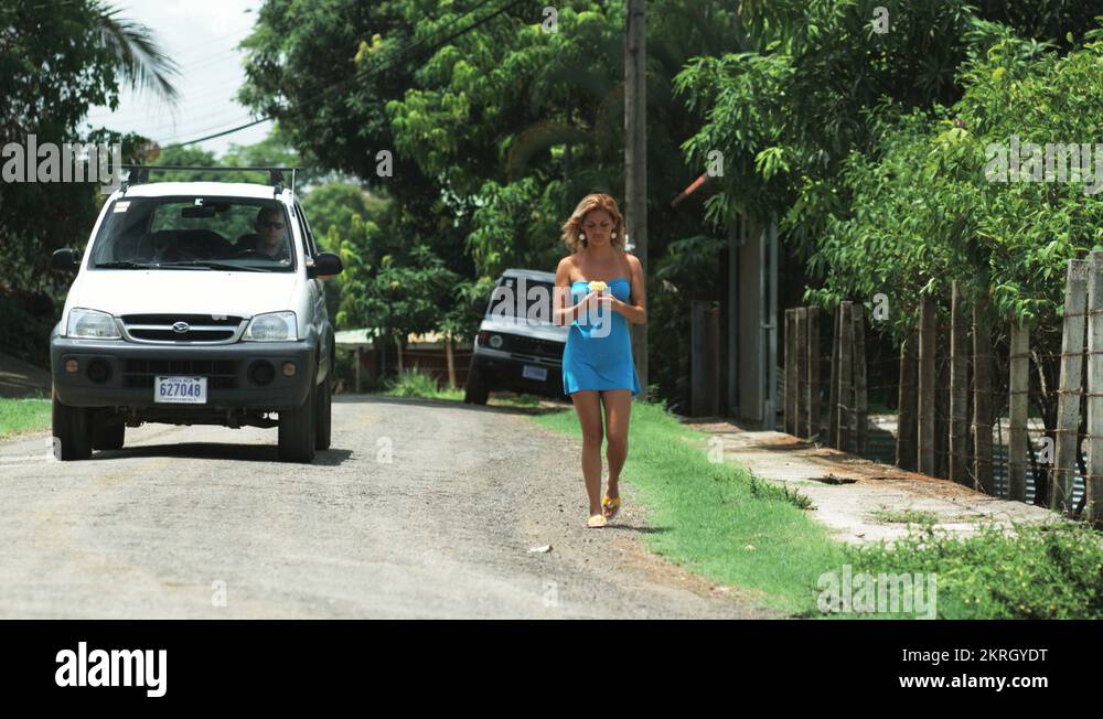 woman walking down the road ignoring a man who is talking to her from ...