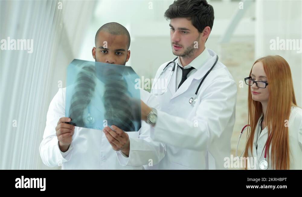 Three confident doctor examining x-ray snapshot of lungs in hospital ...