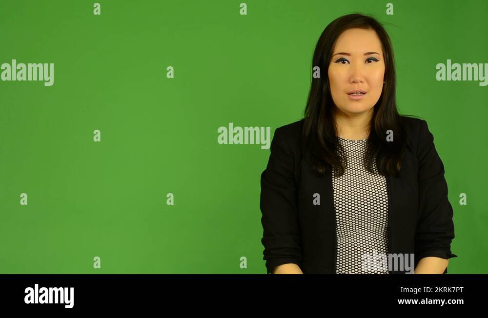 young attractive asian woman talks to camera - green screen studio ...