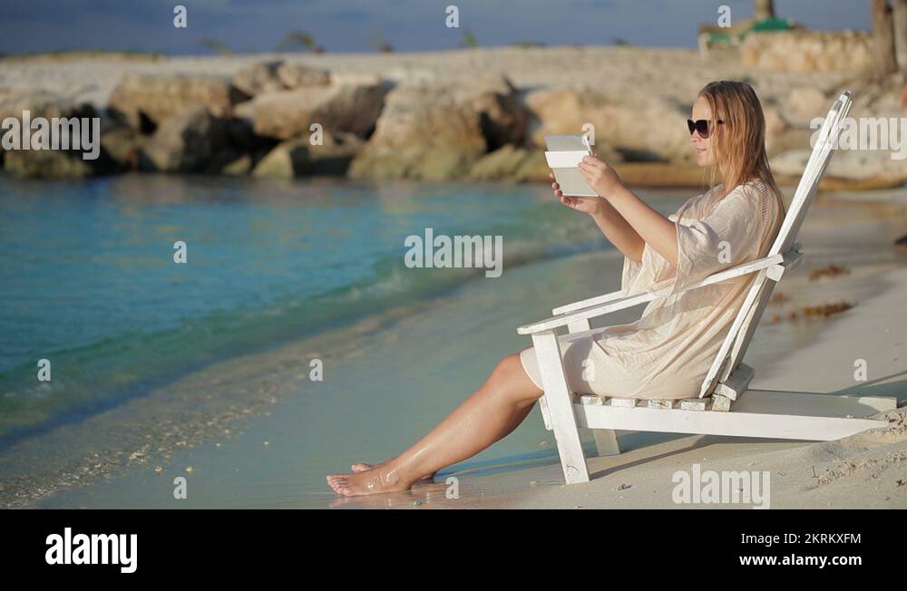 Woman with pad making photos of sea sitting in the deck chair on beach ...
