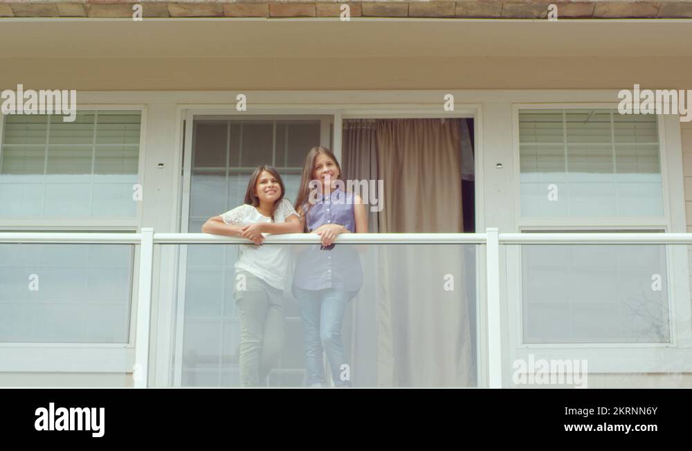 Two sisters hugging and smiling as they stand on the balcony of their house Stock Video Footage ...