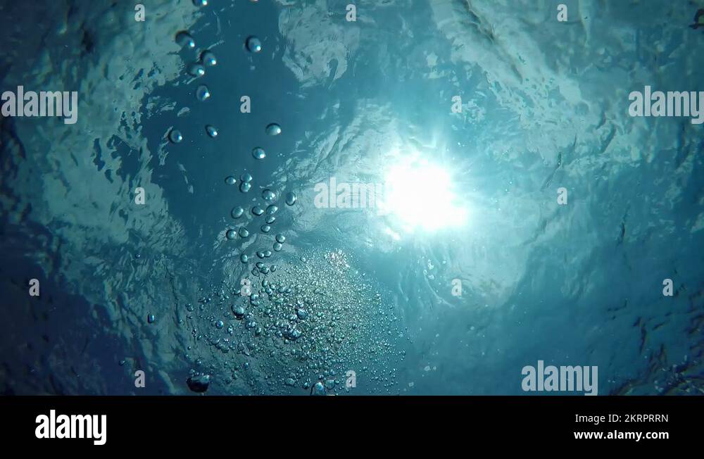 Scuba diver bubbles rising to ocean surface silhouette against sun ...