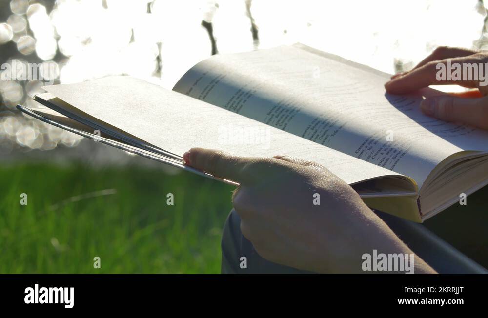 The woman read the book by green grass and water surface texture ...