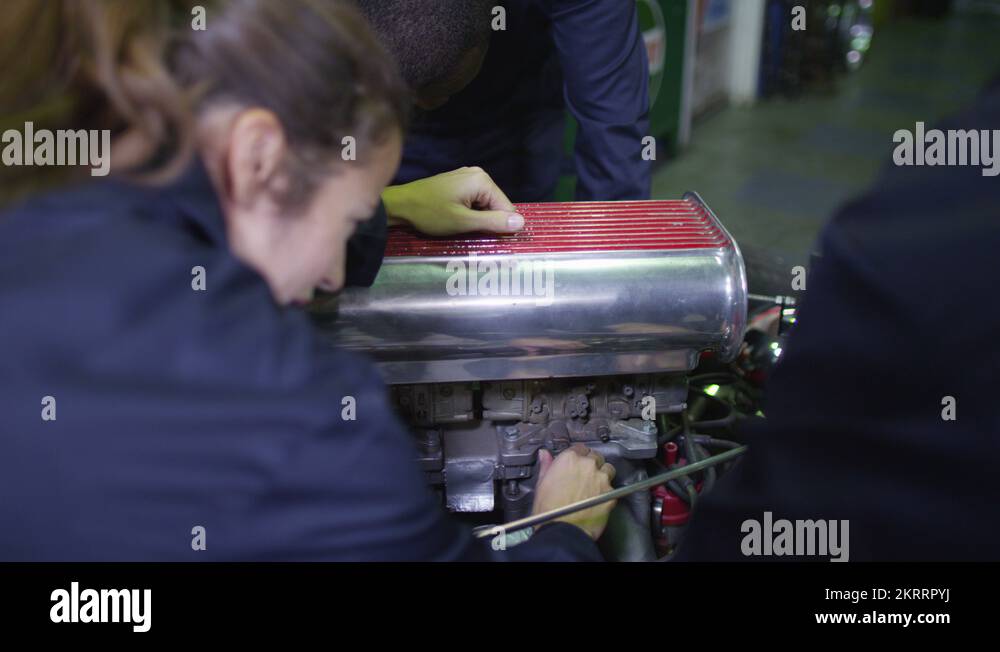 4K Team of male and female mechanics working on a car engine in garage ...