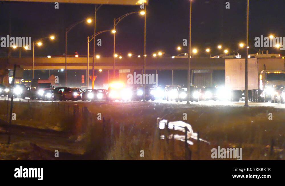 Emergency vehicle travelling on shoulder on a jammed highway at night ...