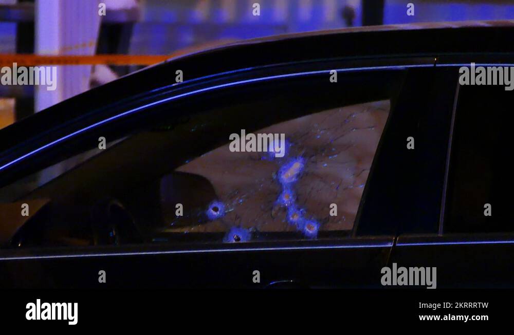 Bullet holes in car window at night with police lights and tape ...