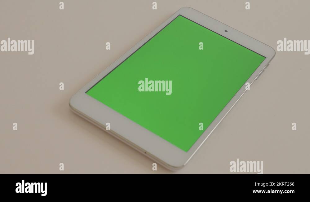 Tablet PC with green screen display on white surface 4K 2160p UltraHD ...