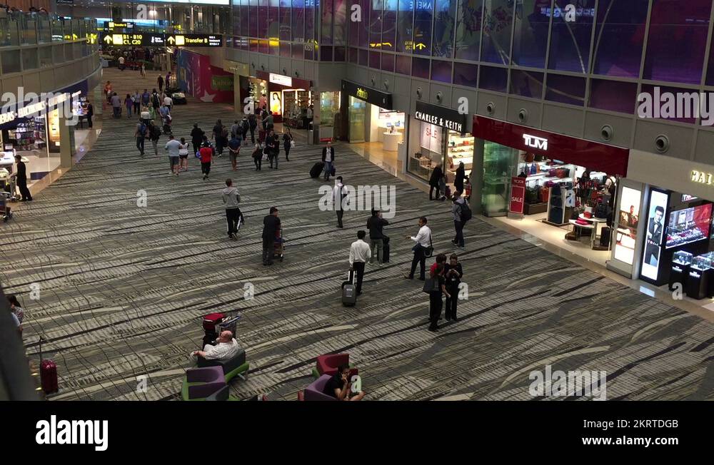 Passengers with luggage walk around shops at Singapore Changi Airport ...