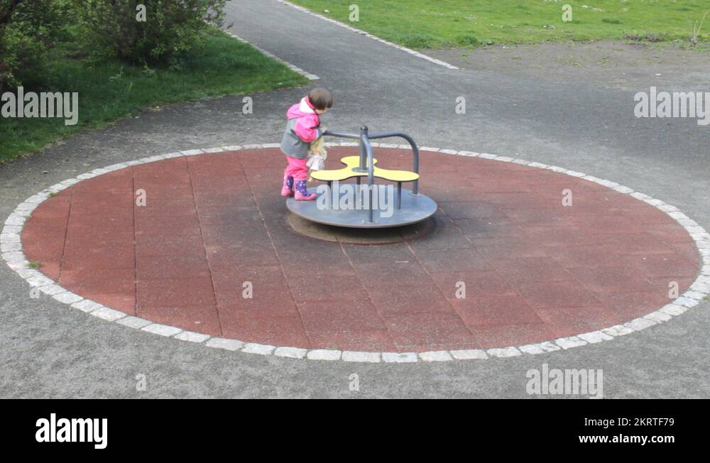 Little girl and merry go round carousel spinning in kids playground ...