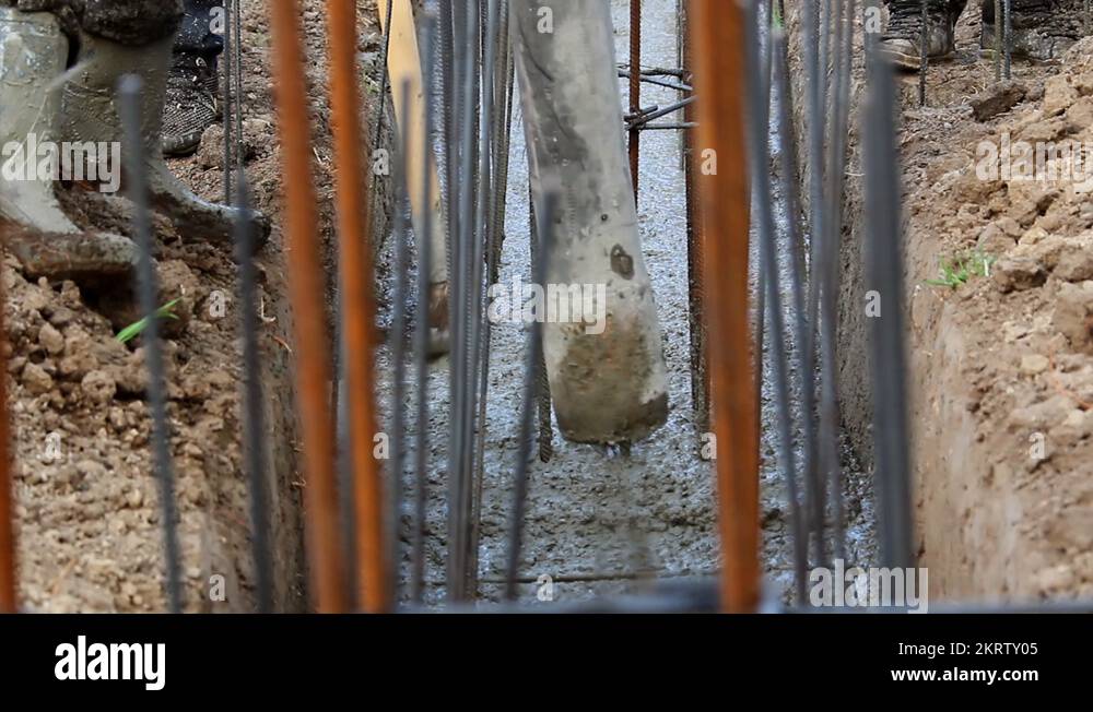 Worker pouring cement and concrete with pump tube into formwork ...