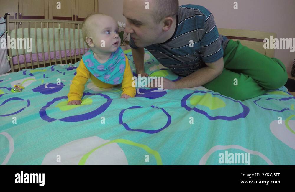 Father man help his baby daughter turn over on bed at home. 4K Stock ...