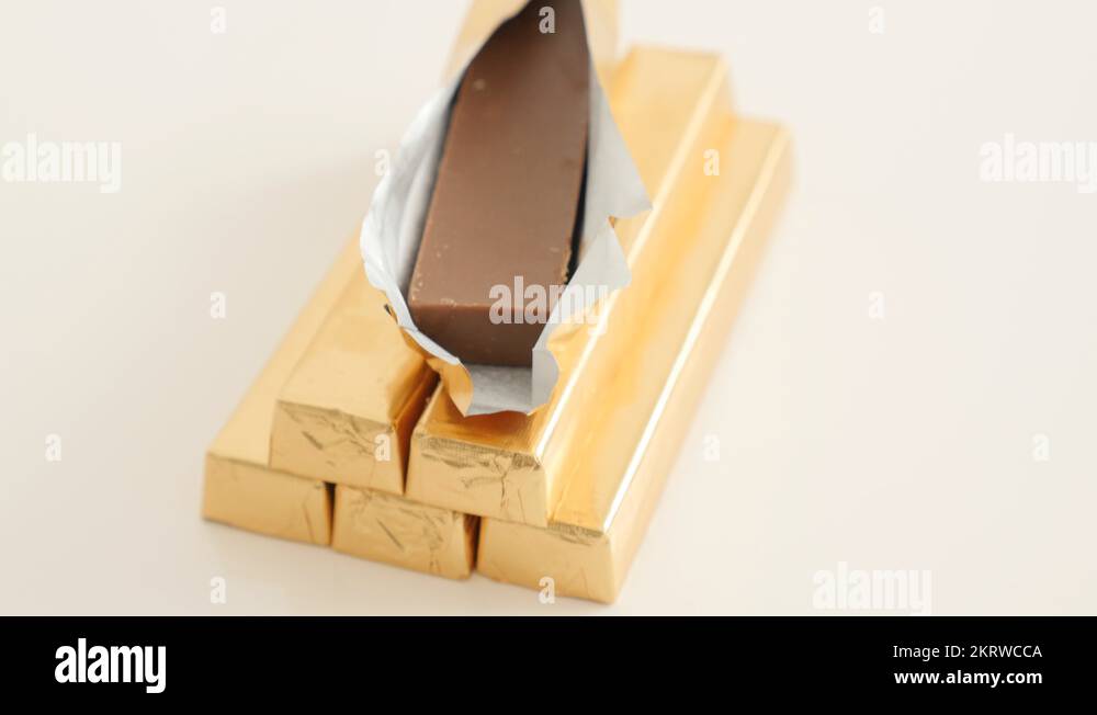 Golden paper wraped chocolate bars on white with one opened background ...