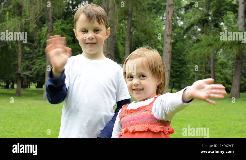 childrens (young boy and little girl (siblings)) wave with hands and ...