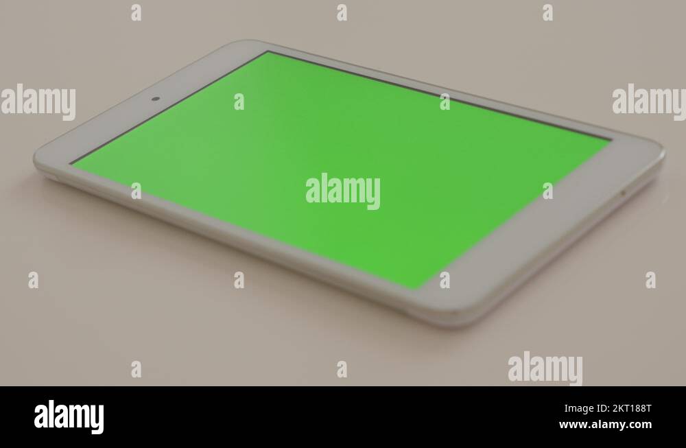 Silver tablet PC with green screen on display tilting on white surface ...