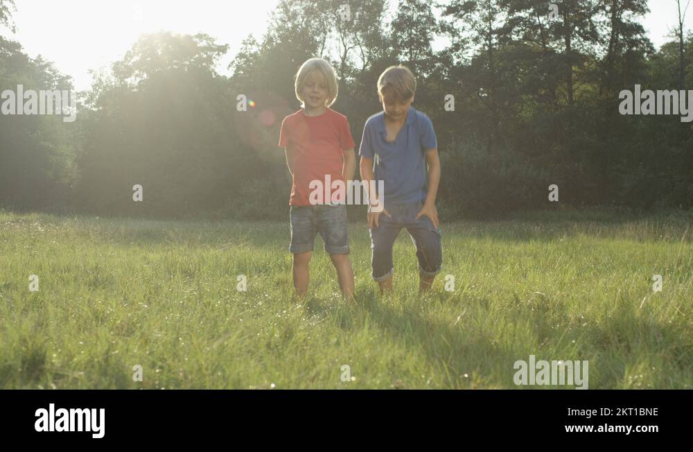 Two kids jumping in puddle splashing water Stock Video Footage - Alamy