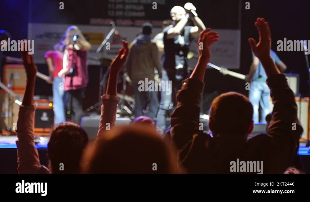 Young fan silhouettes cheering clapping hands up in air on a concert ...