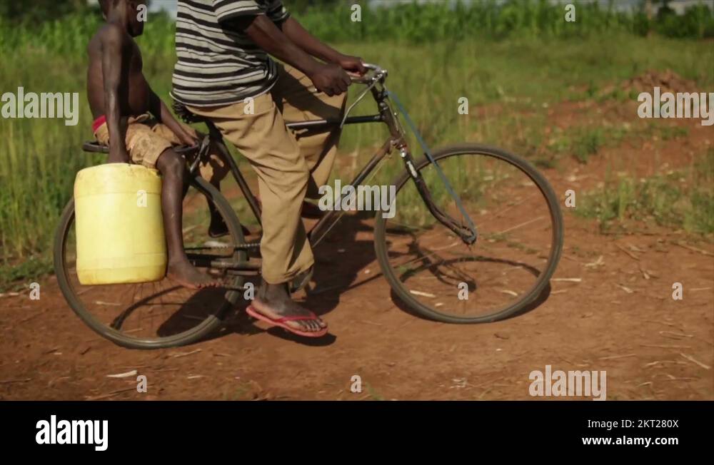 African man on push bike with a child holding a water container Stock ...