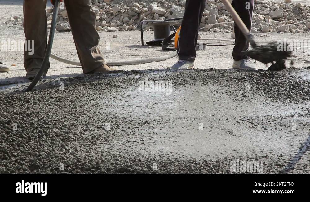 Construction workers compacting liquid cement into a runway ...