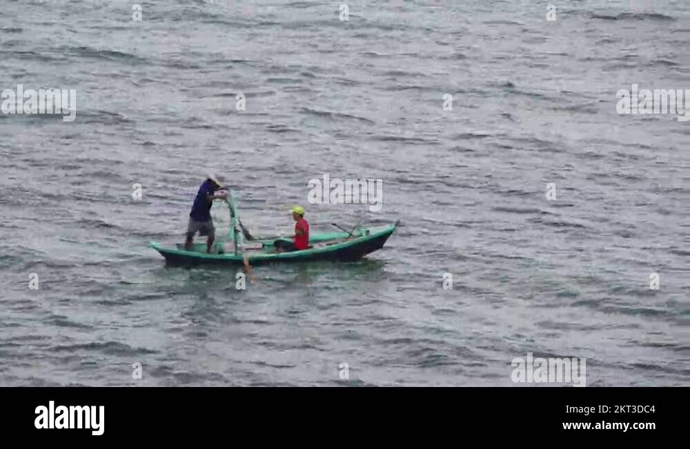 Two men at sea in small and unstable rowboat returning to shore at ...