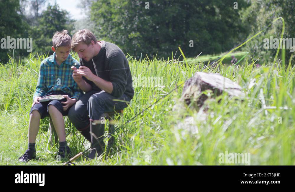 4K Man and young boy together on fishing trip, putting fishing flies on ...