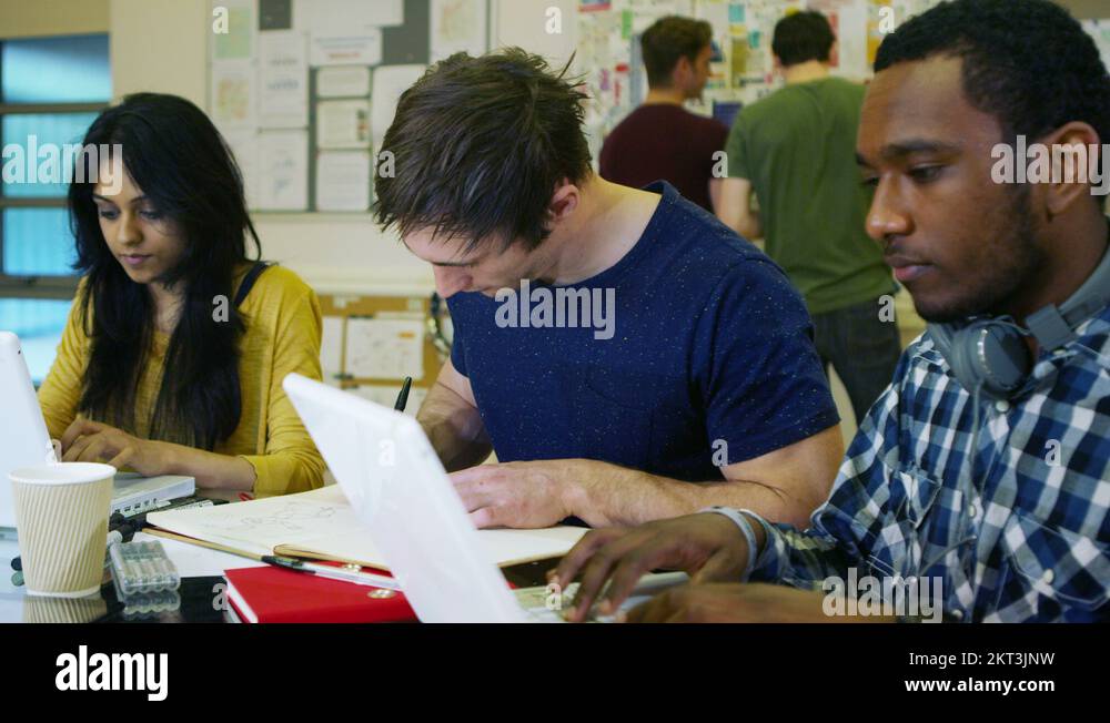 4K Portrait of smiling male student working in class with other ...